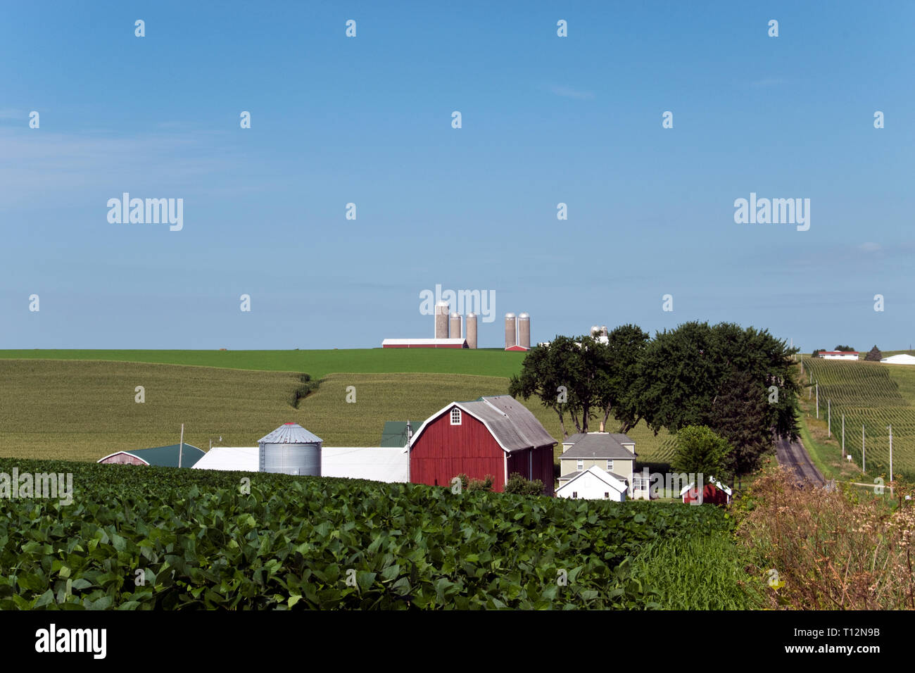 Farm fields with a red barn, grain silos, and a country road in ...