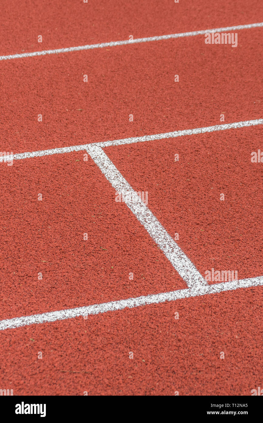 Red coloured all-weather running track. Metaphor 'go the distance ...
