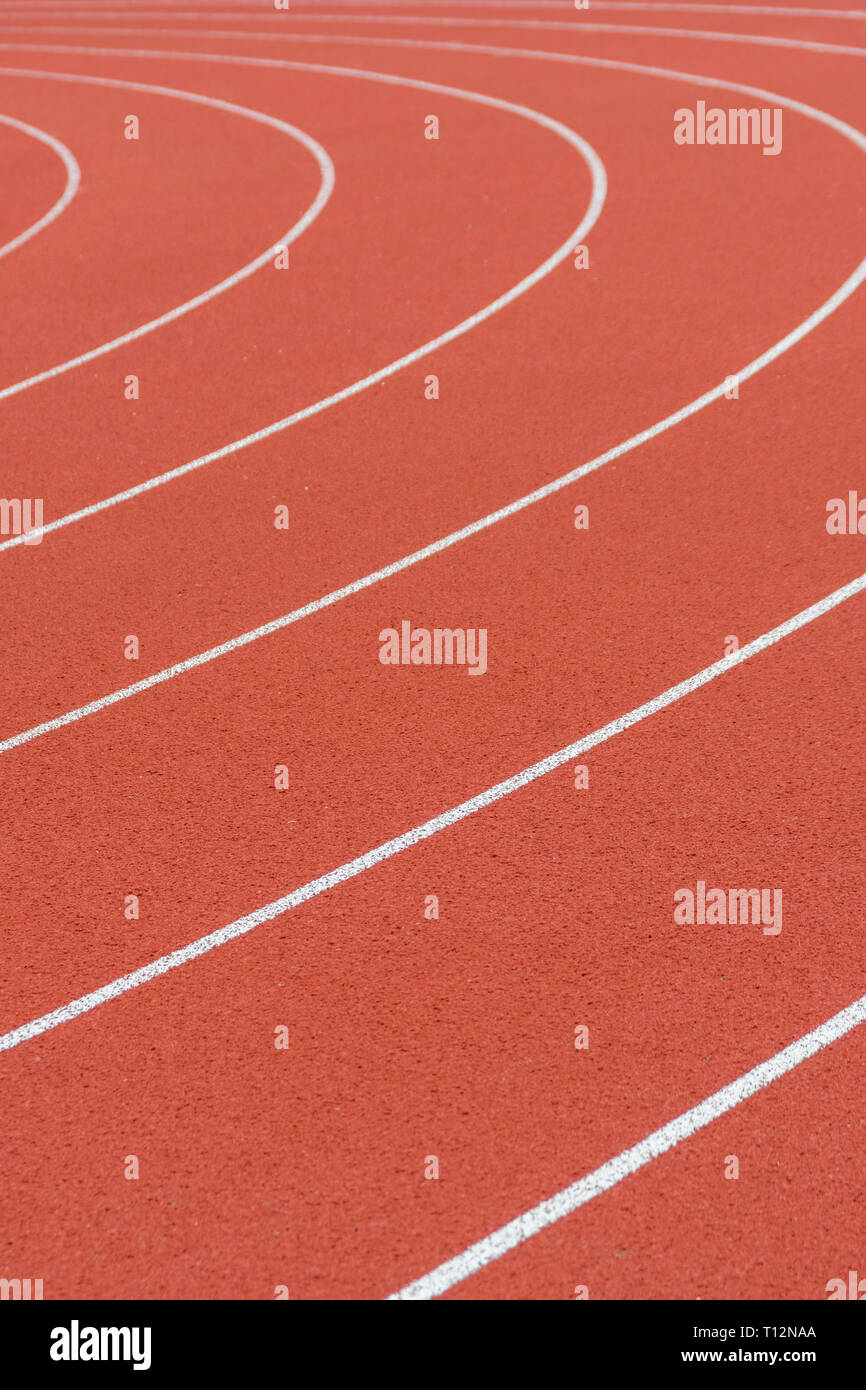 Red coloured all-weather running track. Metaphor 'On Track', go the ...