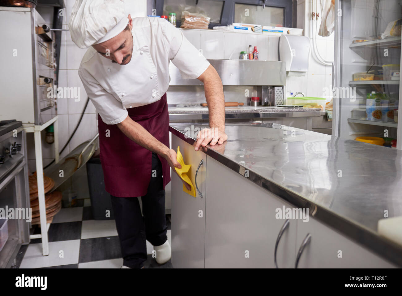 young chef in kitchen wiping cabinets, after closing restaurant Stock ...