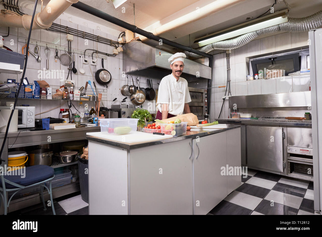 One young chef, 20-29 years old, standing in a commercial kitchen ...