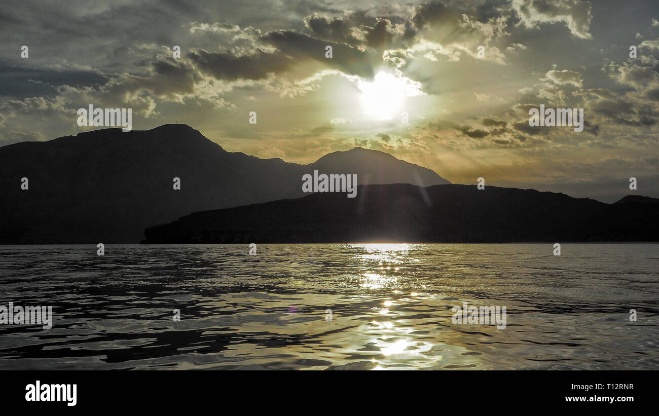 Sun on the background of mountains and the sea. Fjords of the Musandam ...