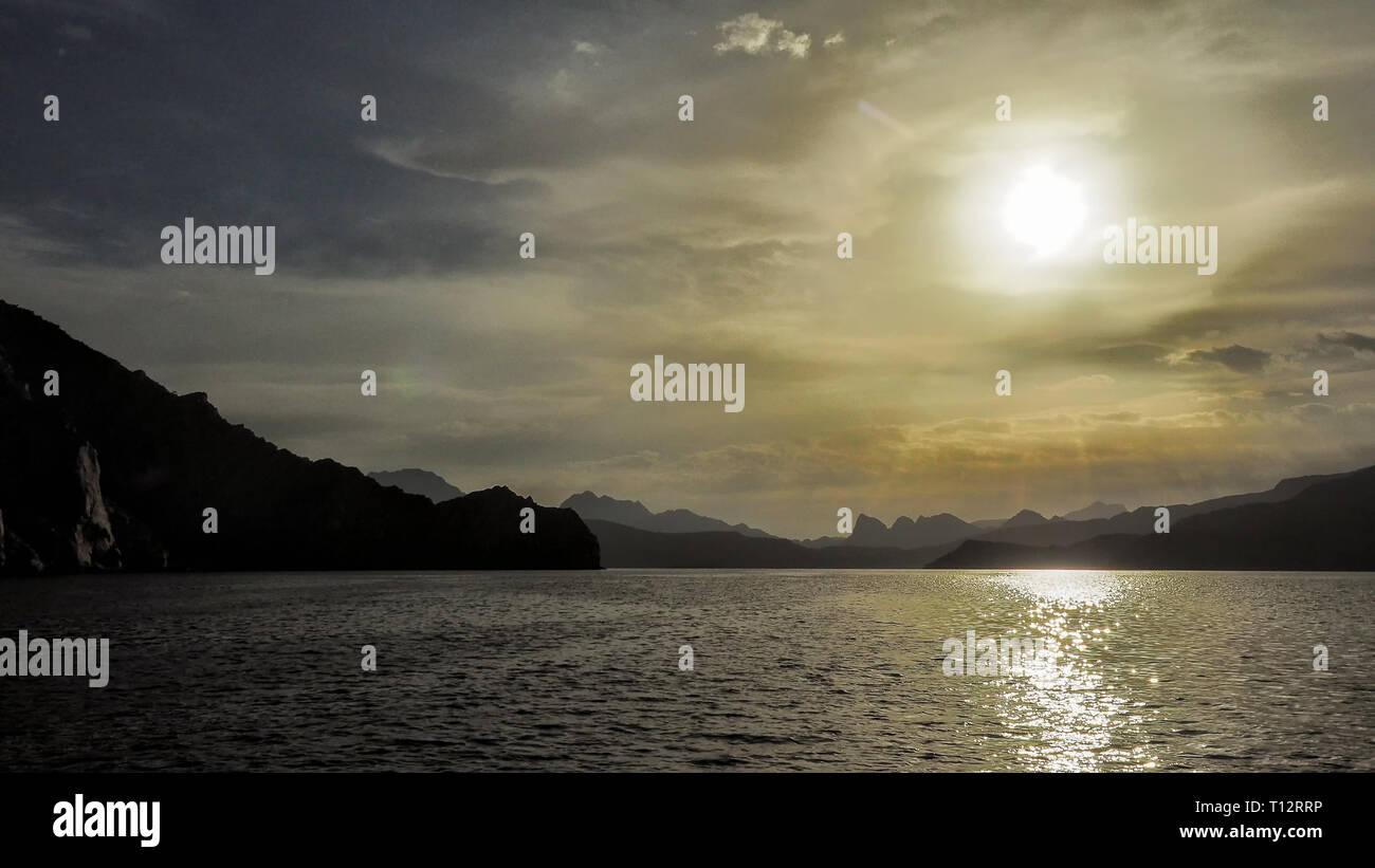 Sun on the background of mountains and the sea. Fjords of the Musandam ...
