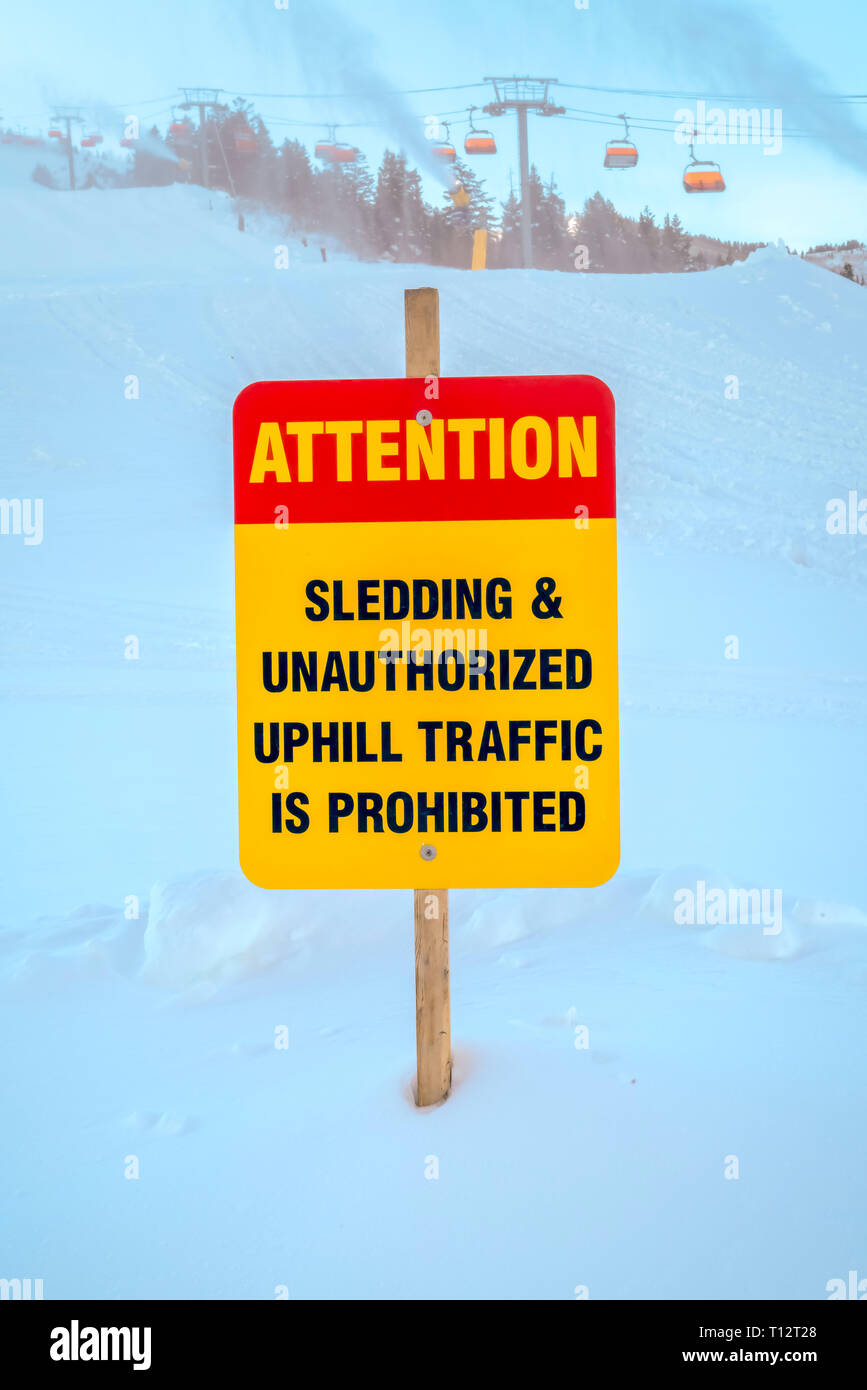 Attention sign against snow at a ski resort. Sign that reads Attention ...