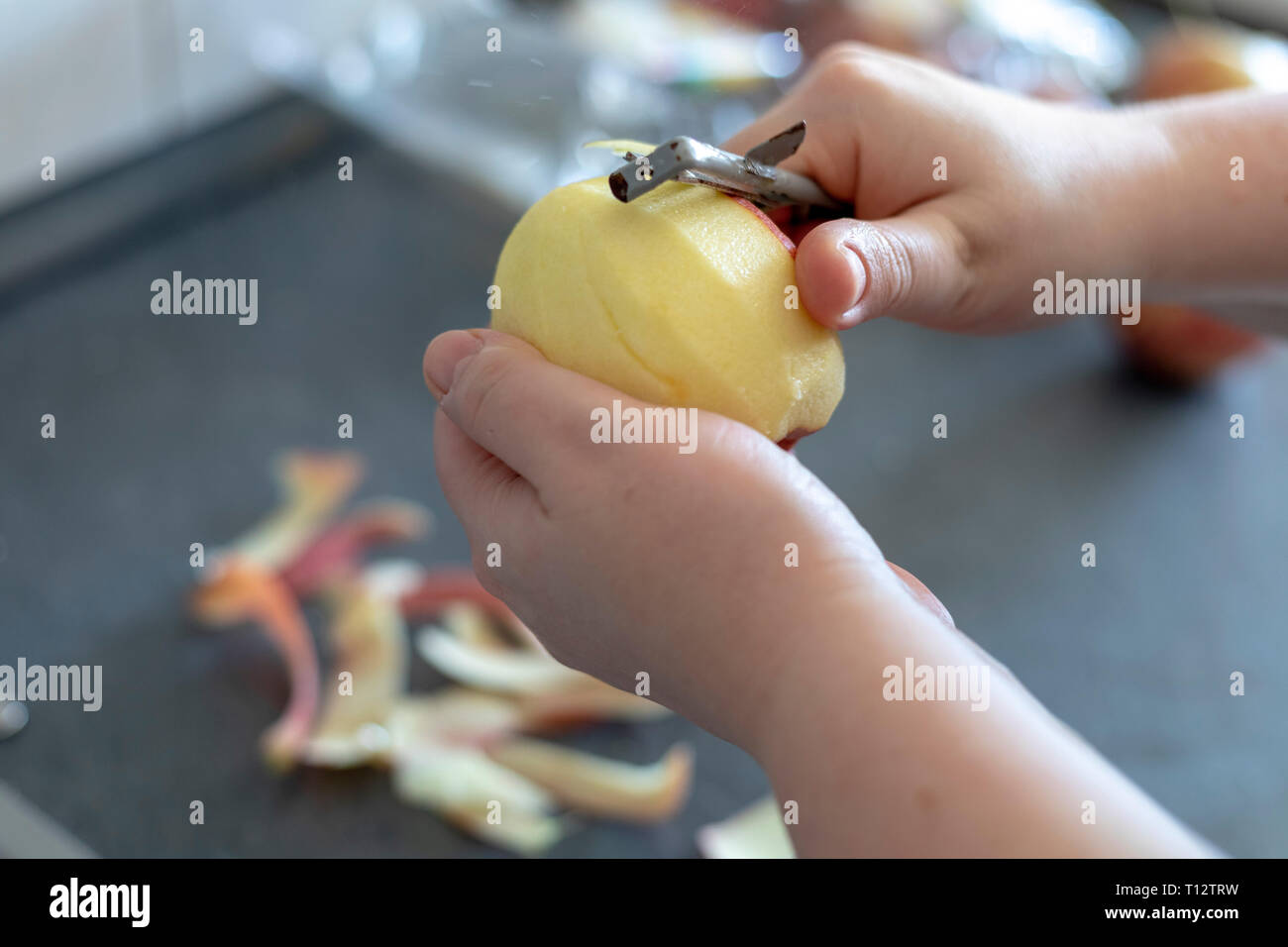Hands peeling a cooking apple on a grey background Stock Photo - Alamy