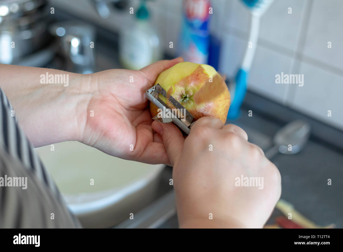 Hands peeling a cooking apple on a grey background Stock Photo - Alamy