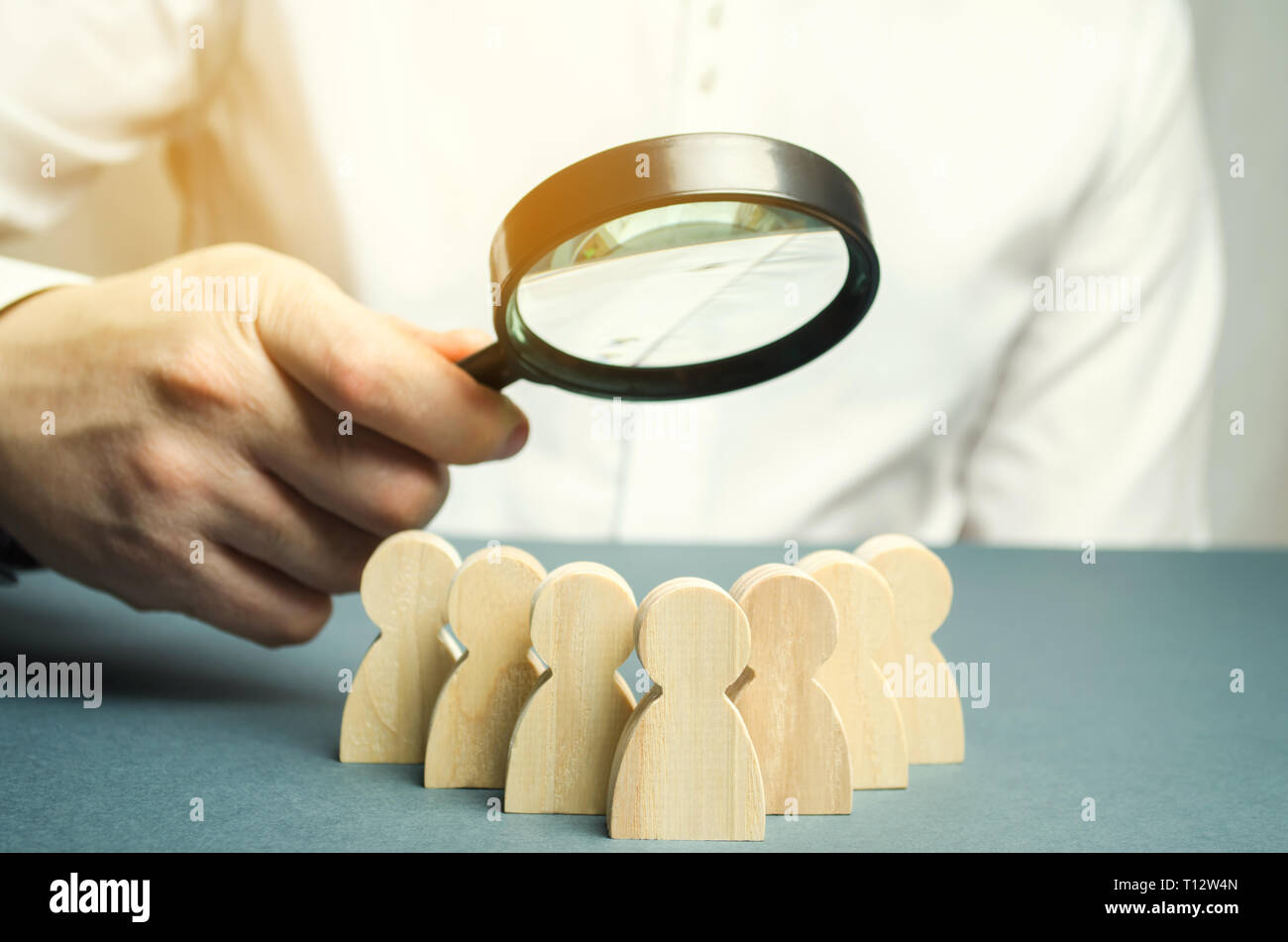 Business leader holding a magnifying glass over a team of workers. The ...