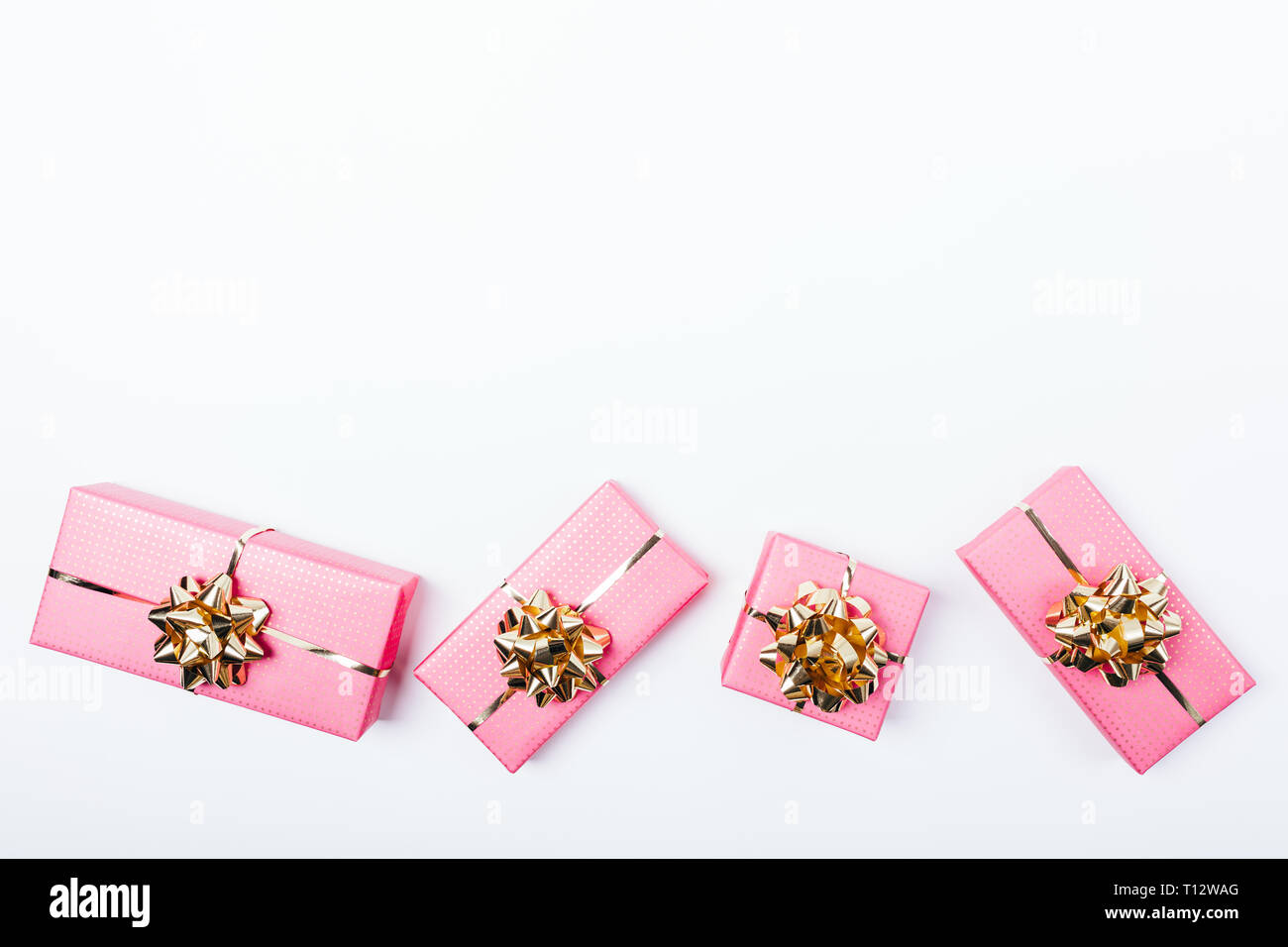 Flat lay arrangement of bright pink packaged gifts with golden bows on ...