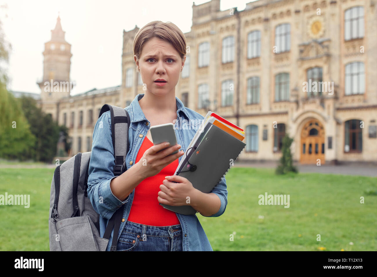 Young female student carrying backpack at university campus walking ...