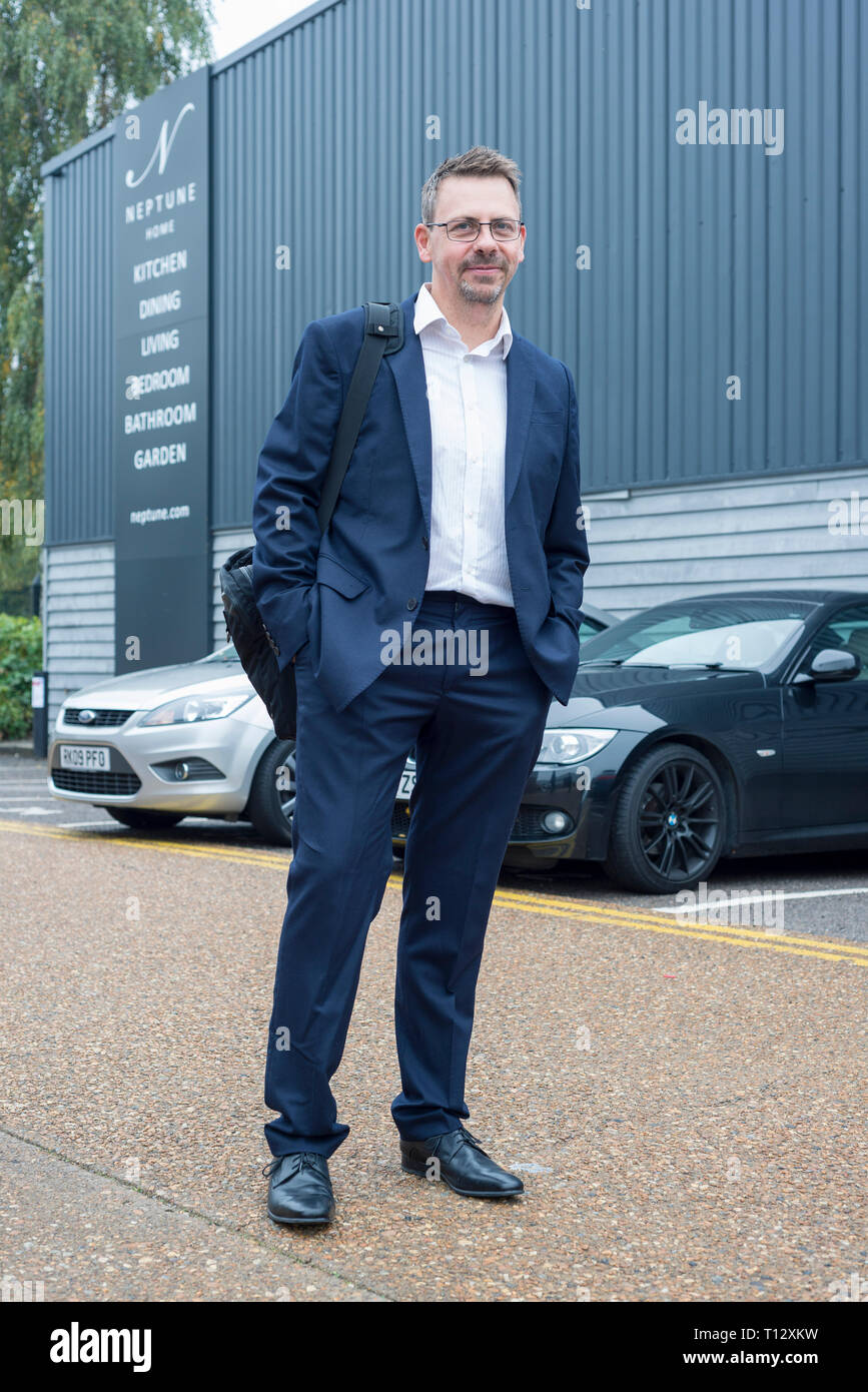 A businessman standing while wearing a suit and looking smart in a ...