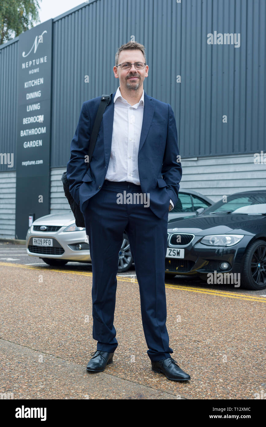 A businessman standing while wearing a suit and looking smart in a ...