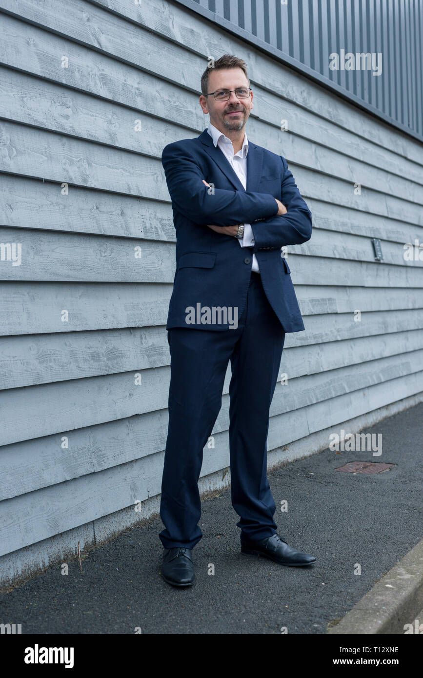 A businessman standing while wearing a suit and looking smart in a ...