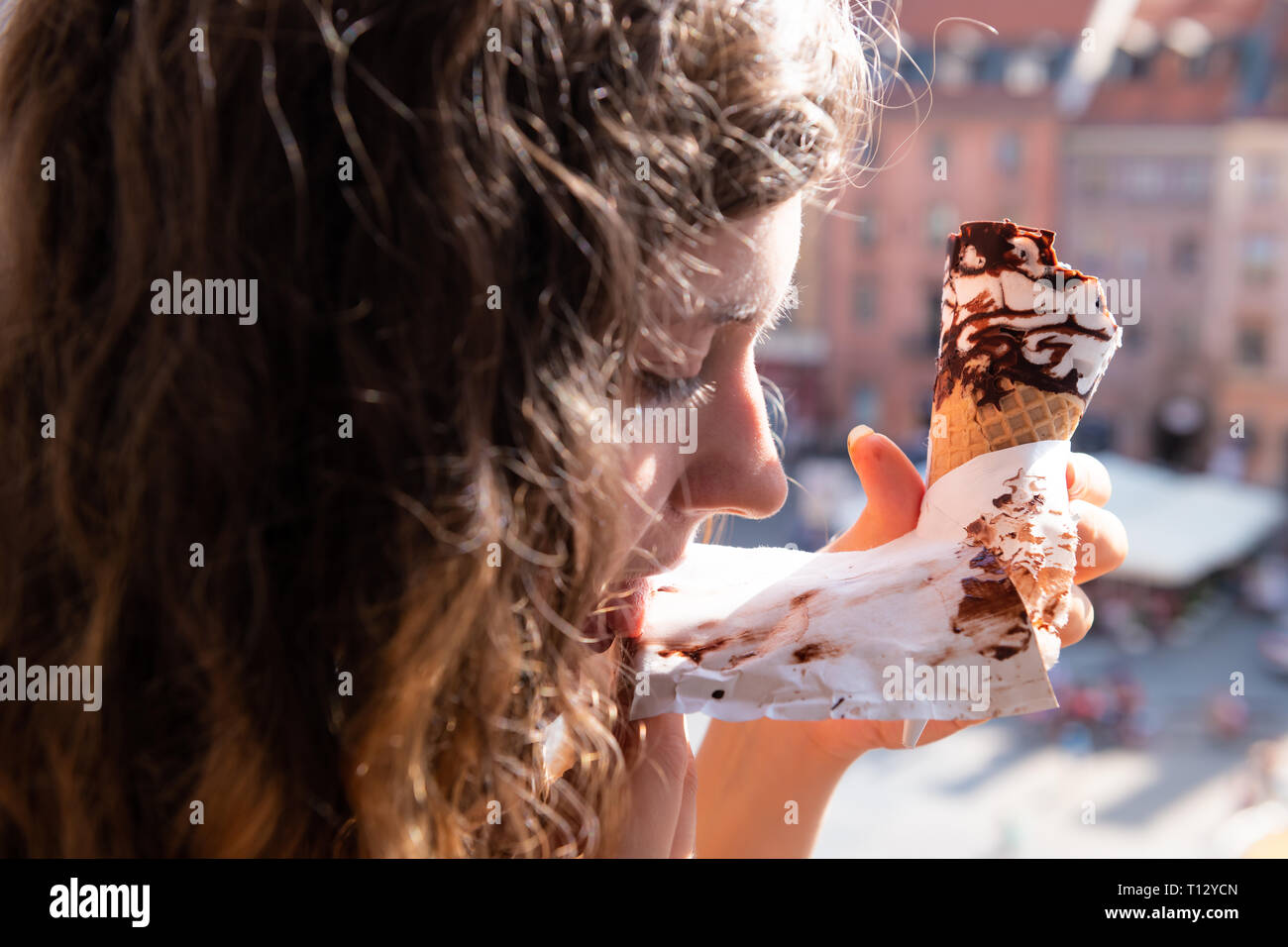 Woman eating chocolate ice cream gelato cone paper licking with ...