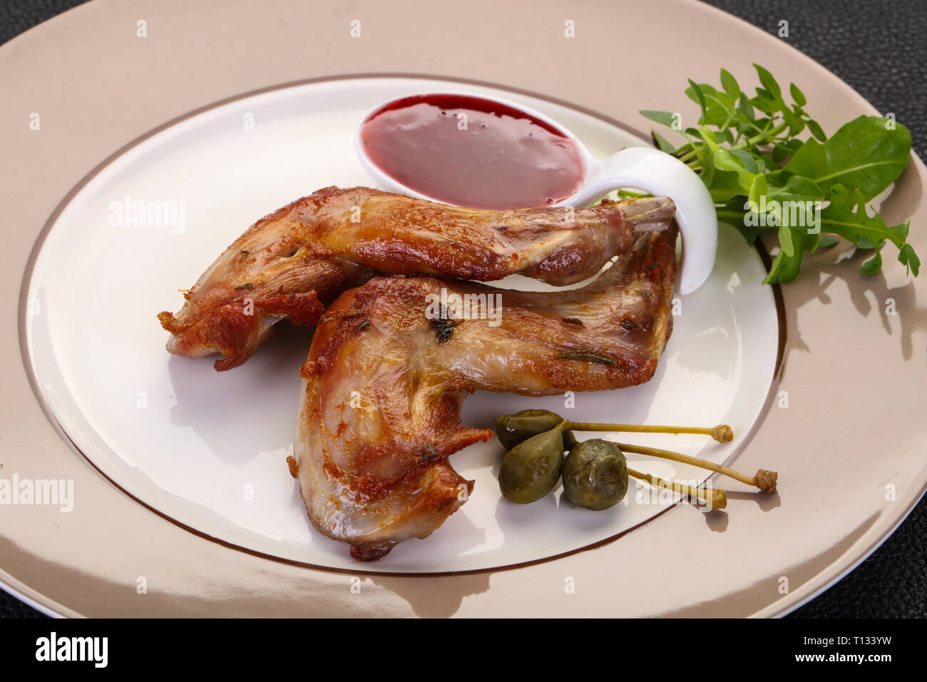 Roasted rabbit legs with cowberry sauce Stock Photo - Alamy