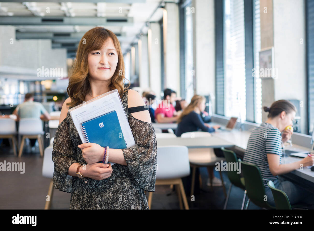 A female Asian student in a modern college campus poses for a photo ...