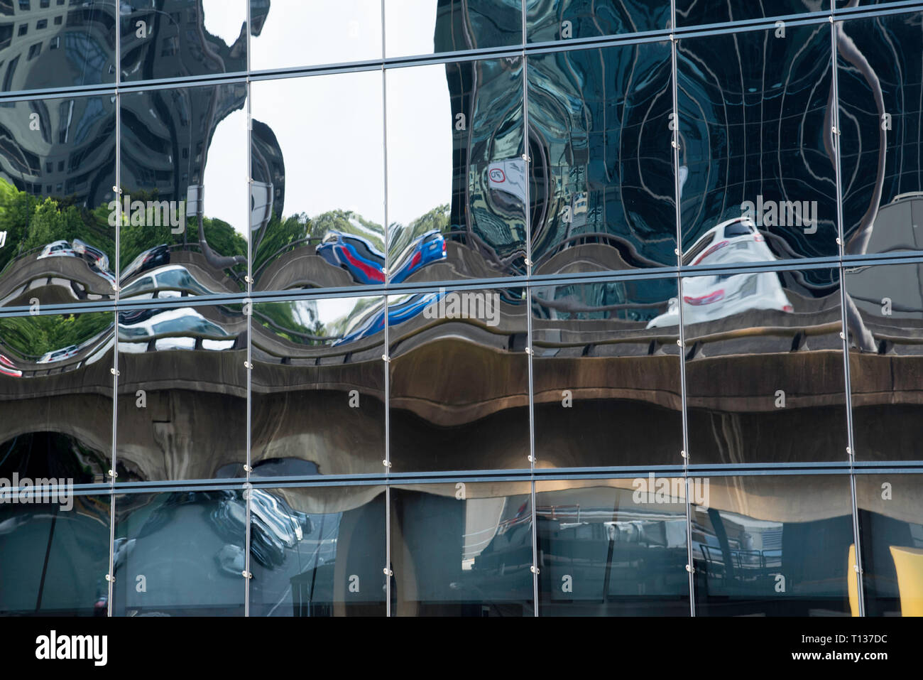 Blurred and distorted cars driving on a bridge and reflected in office ...