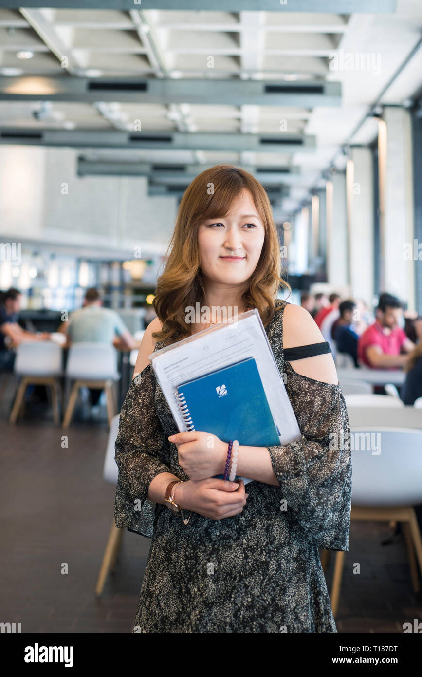 A female Asian student in a modern college campus poses for a photo ...