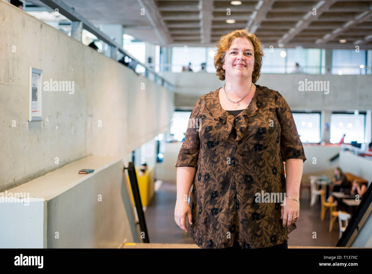 A friendly white lady stands in a modern designed building for a ...
