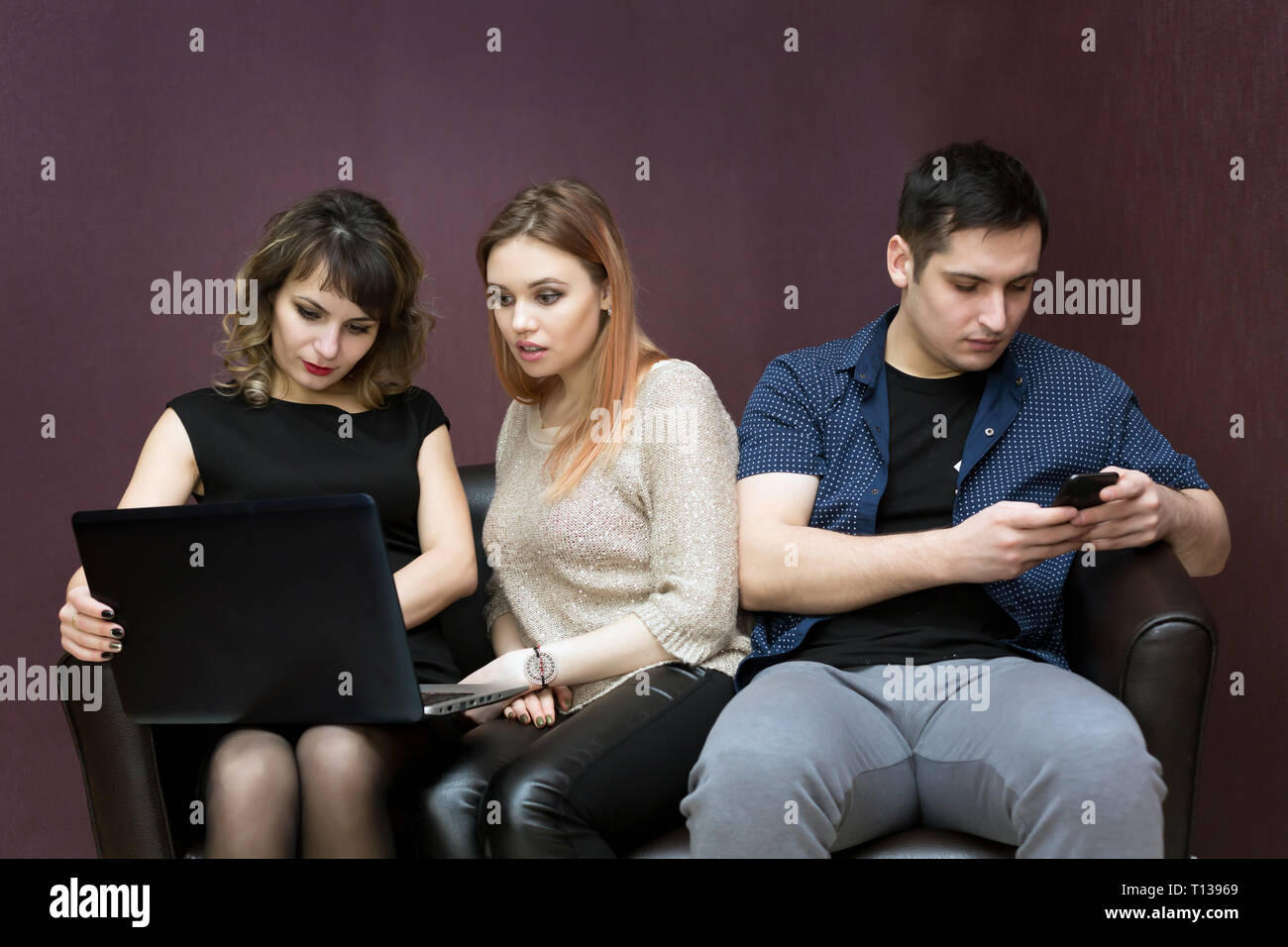 The man is bored looking into the phone and the girls with interest are ...