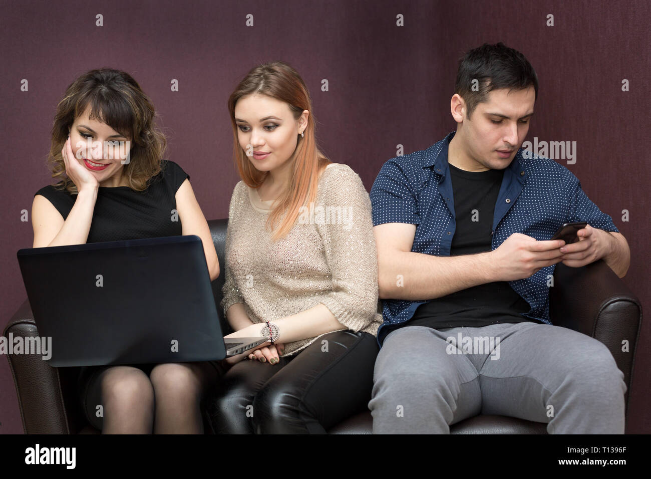 The man is bored looking into the phone and the girls with interest are ...