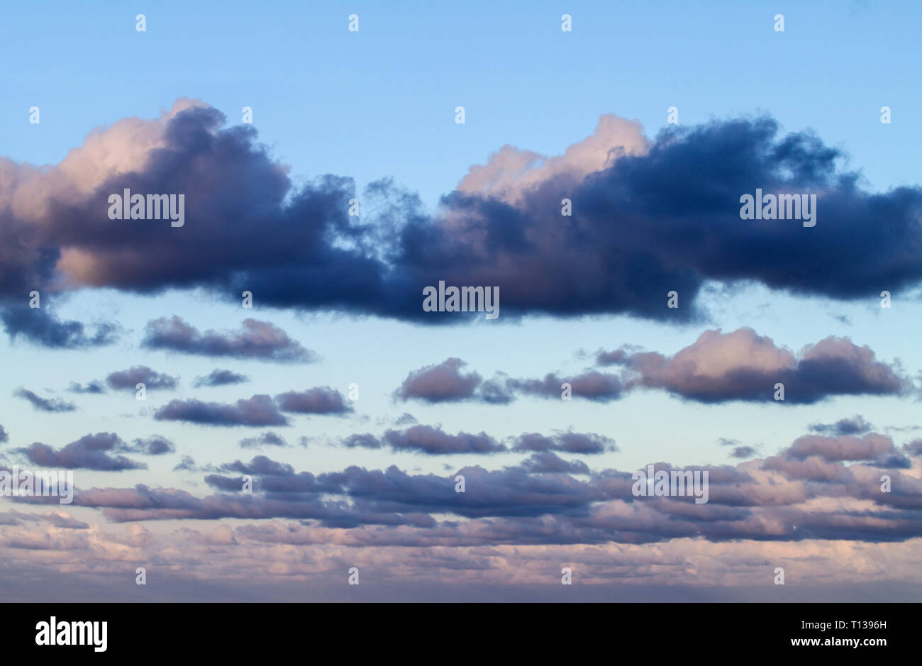 Impressive sky at sunset with layers of clouds tinged with pink that ...