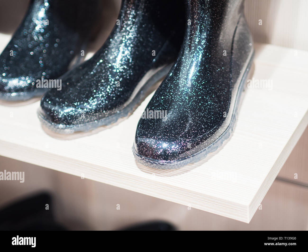 Black glitter rubber boots being sold on a shelf at a fast fashion ...