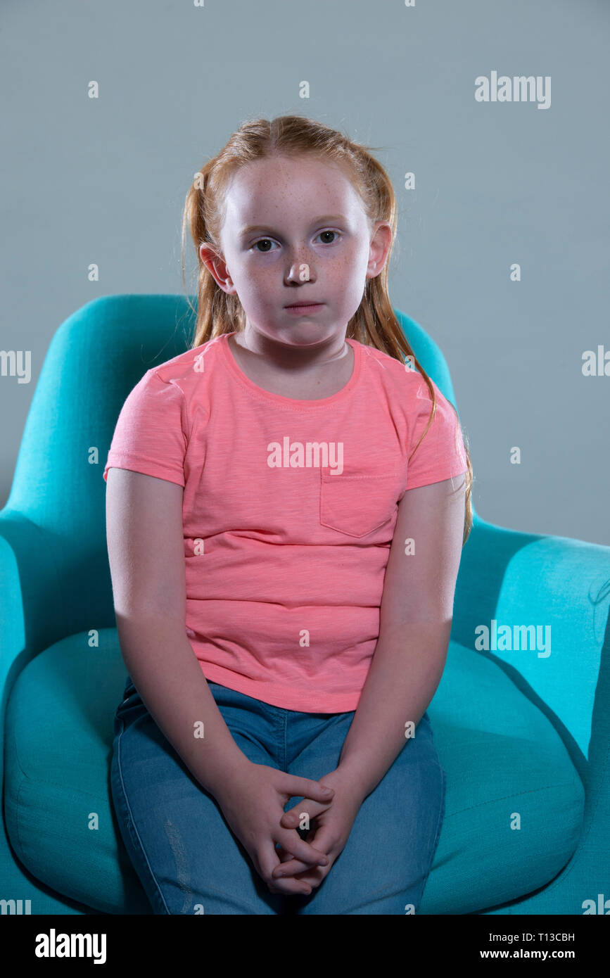 a restless white girl with red hair sat on a chair Stock Photo - Alamy