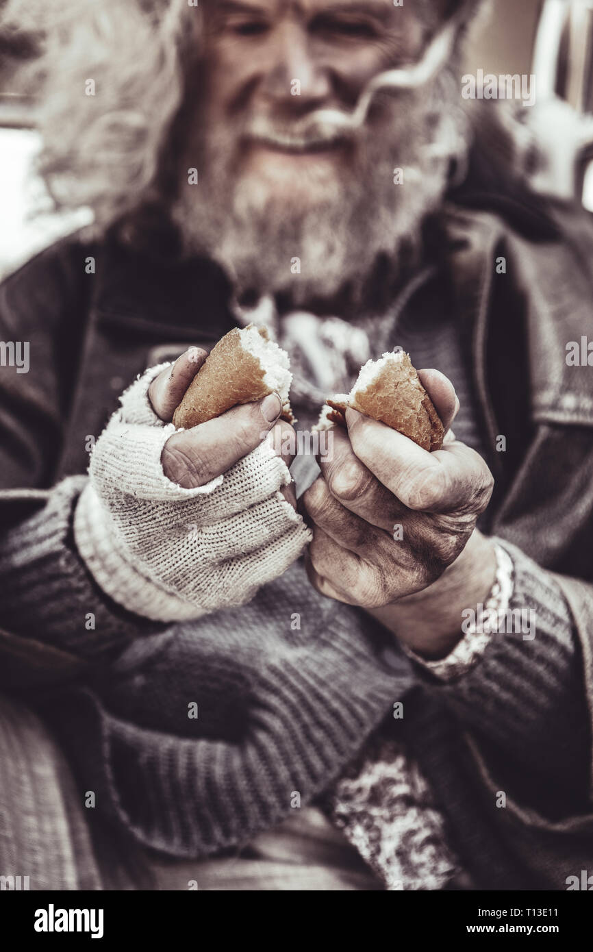 Homeless elderly sitting and sharing sweet bun to two portions Stock ...