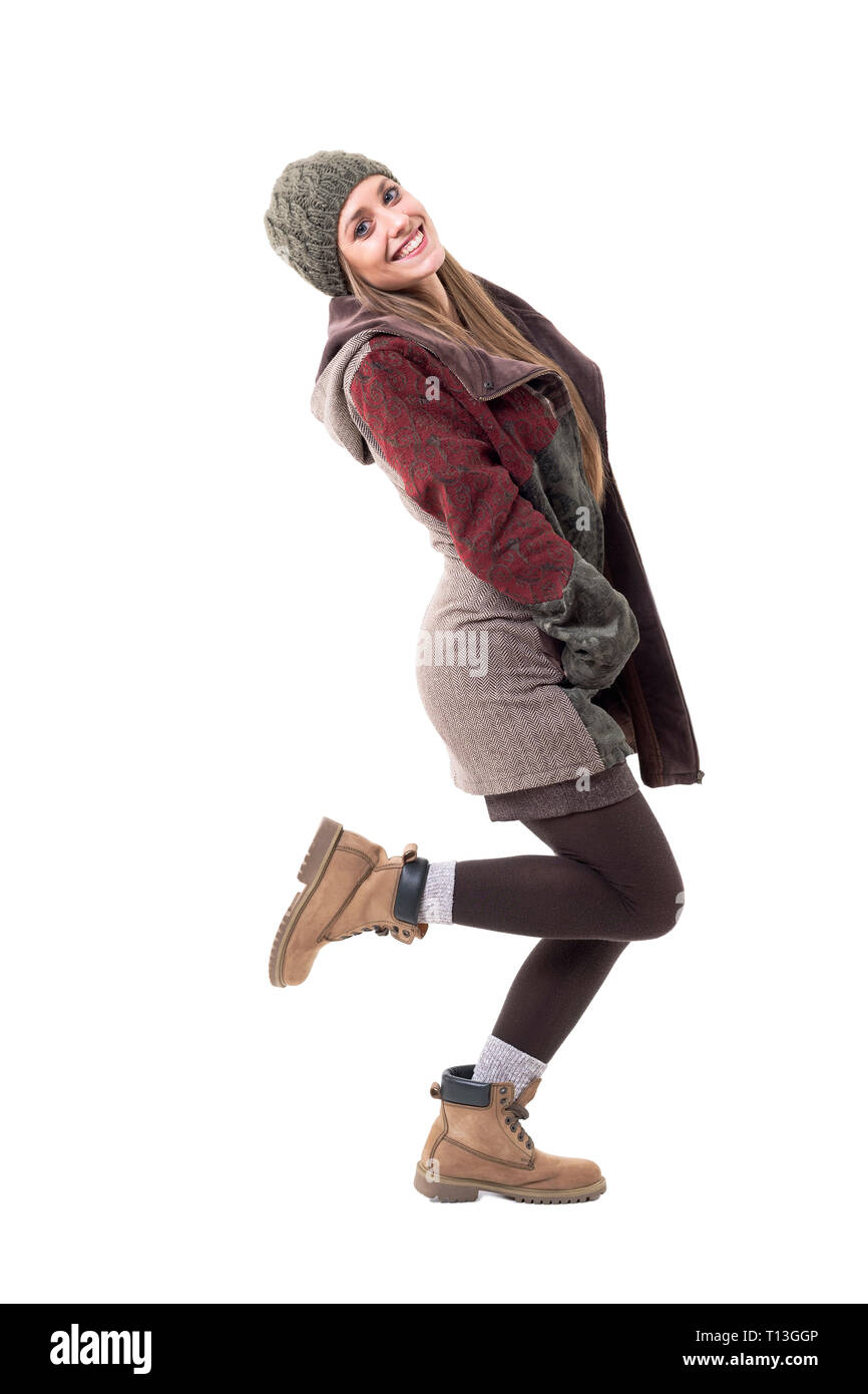 Side view of playful happy woman in warm winter clothes posing on one ...
