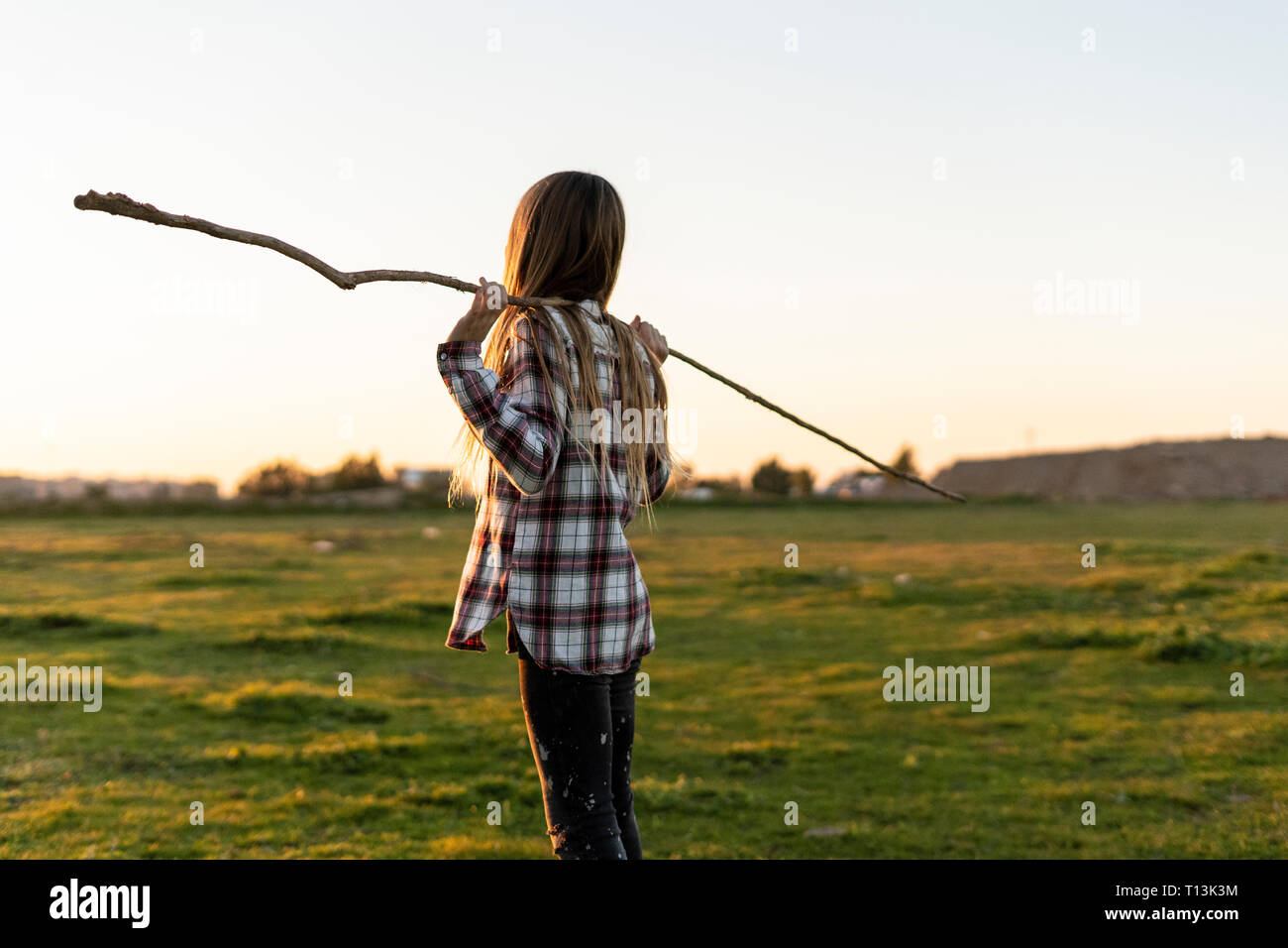 Back view of girl with stick in nature Stock Photo - Alamy