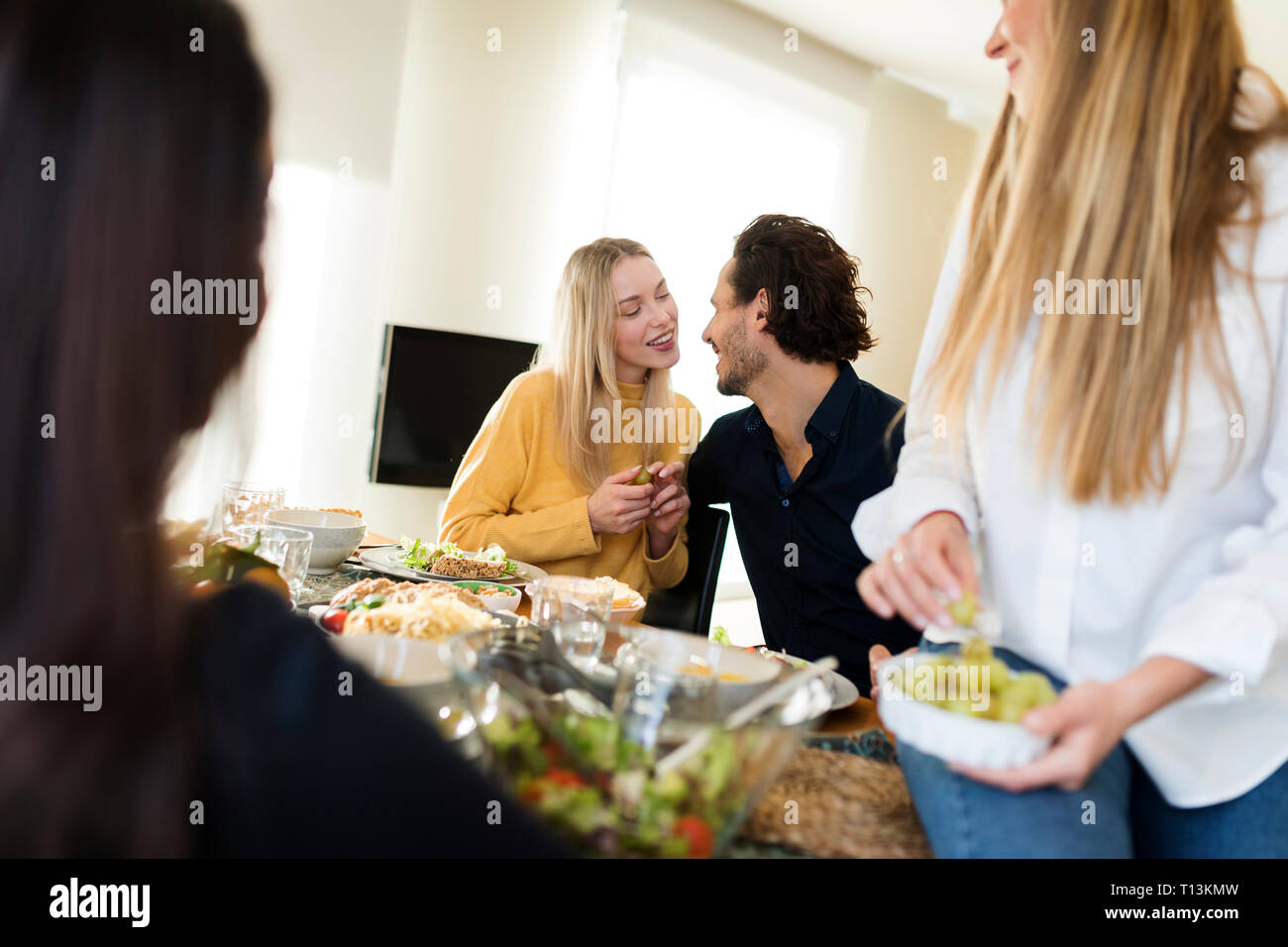 Friends having lunch together, affectionate couple kissing at the table ...