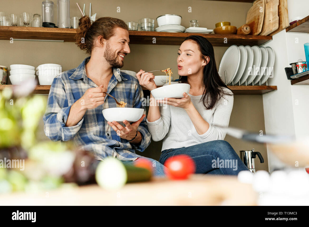 Happy couple sitting in kitchen, eating spaghetti Stock Photo - Alamy