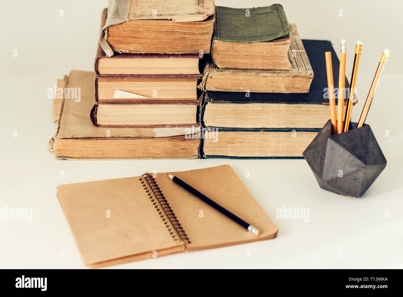 Stack of old books, textbook, glasses and pencils in office background ...