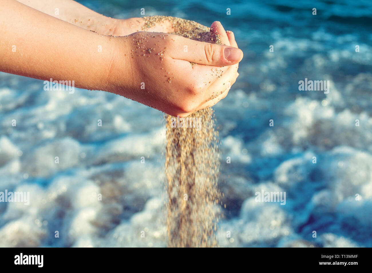 Sand falling from the hands on sea beach background. Happy holiday and ...