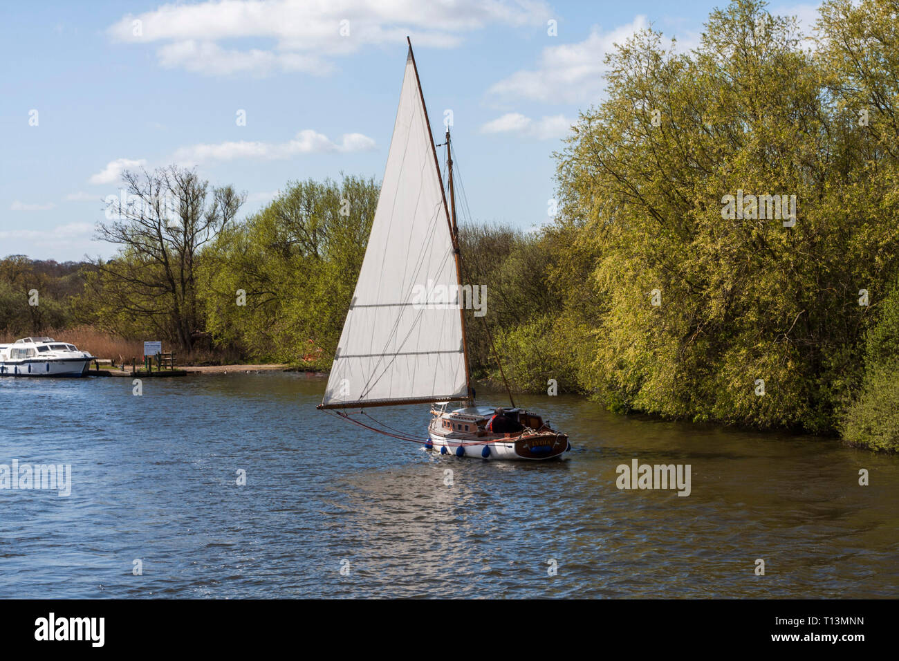 A sailing boat makes it way down the river on the Norfolk Broads ...