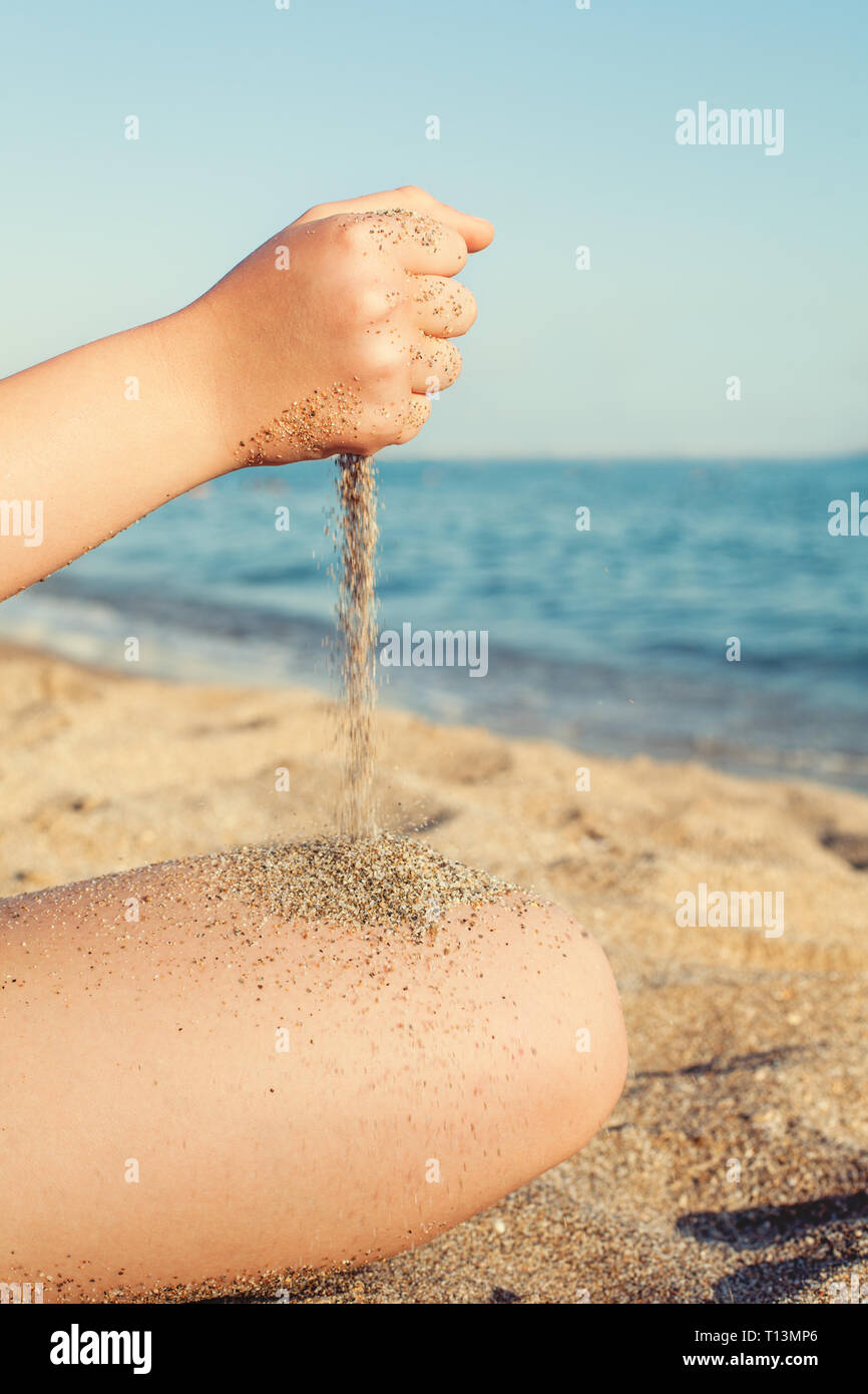 Girl relaxing on sea beach. Sand falling from the female hands on sea ...