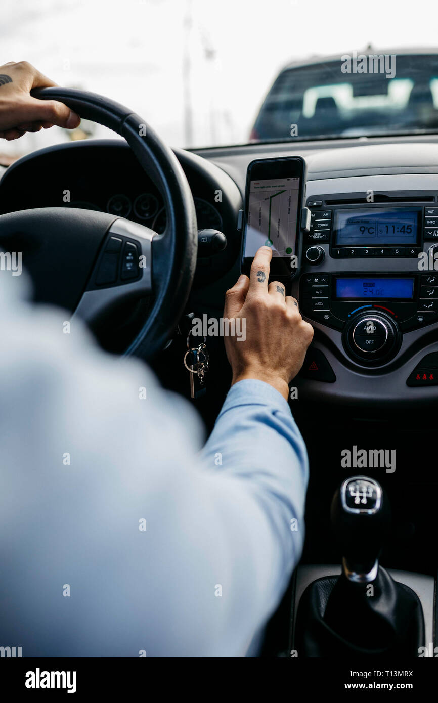Close-up of man with tattooed hand driving car using cell phone as ...