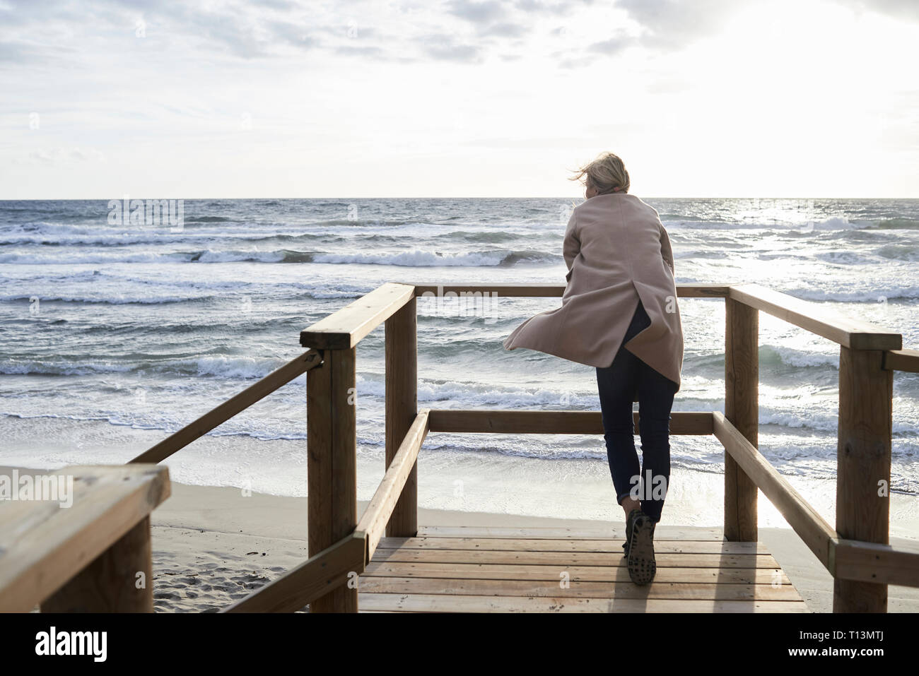 Spain, Menorca, back view of senior woman standing on boardwalk in ...