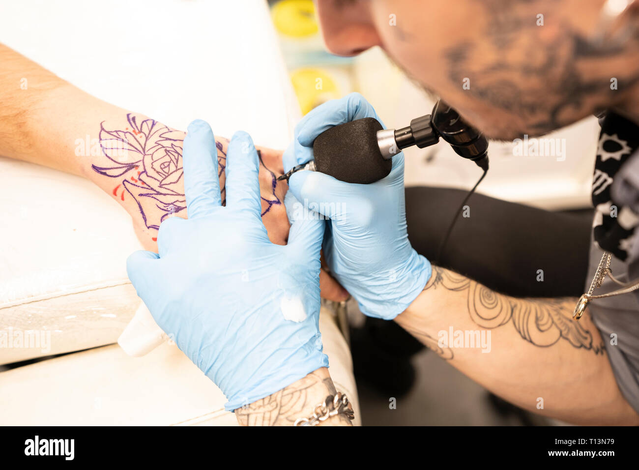 Tattoo artist tattoing hand Stock Photo - Alamy