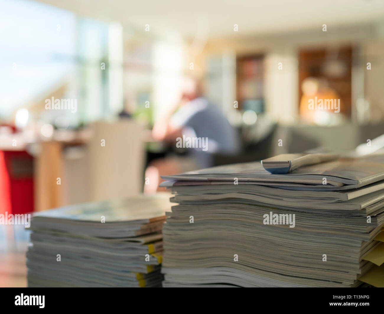 Stack of magazines in living room with man in background Stock Photo ...