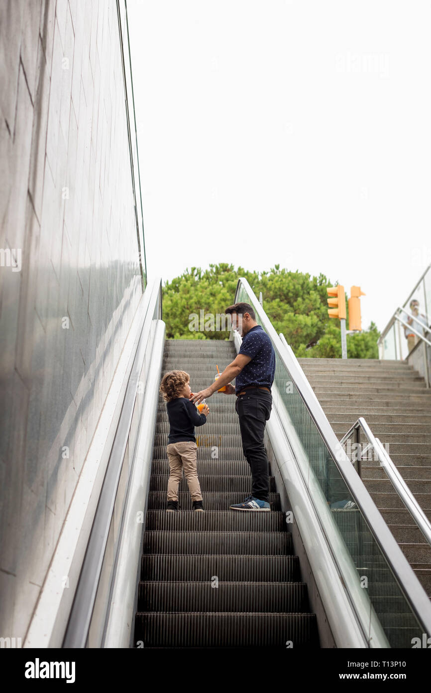 Father and son with soft drinks on escalator Stock Photo - Alamy