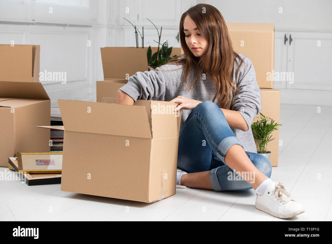 Woman sitting on the floor packing cardboard boxes Stock Photo - Alamy