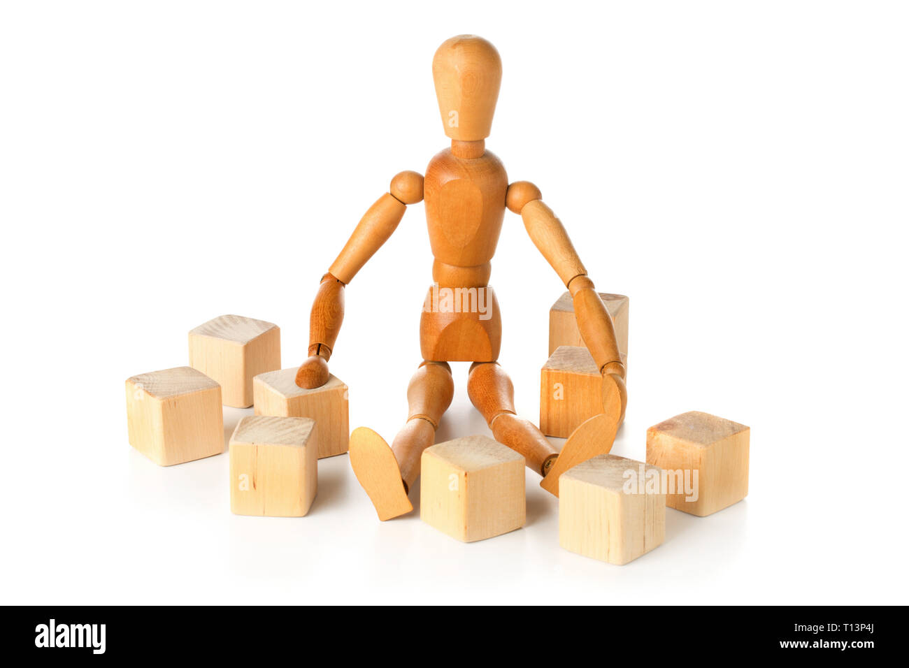 Wooden mannequin sitting in the middle of wooden blocks over white ...
