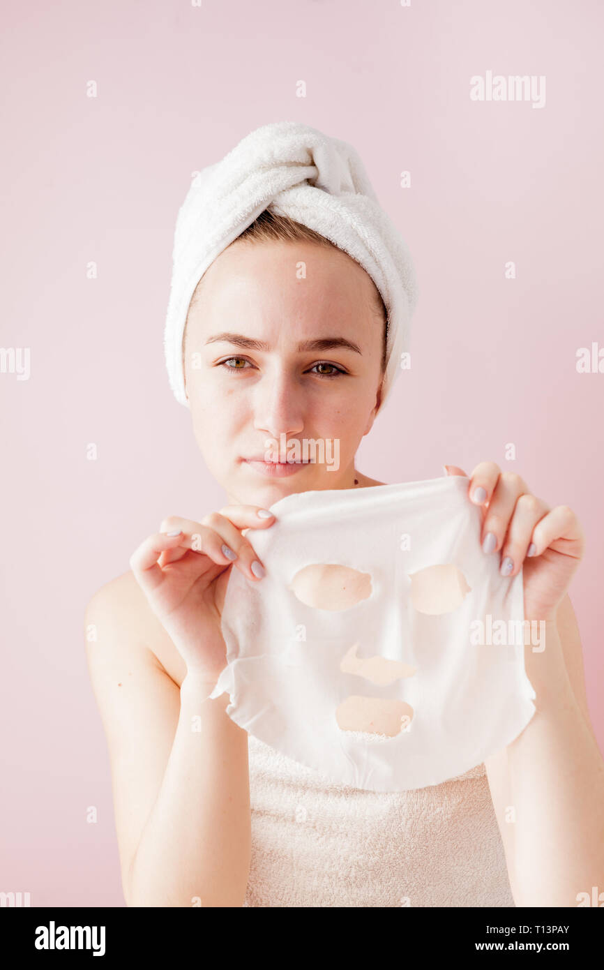 Beautiful young woman is applying a cosmetic tissue mask on a face on a ...