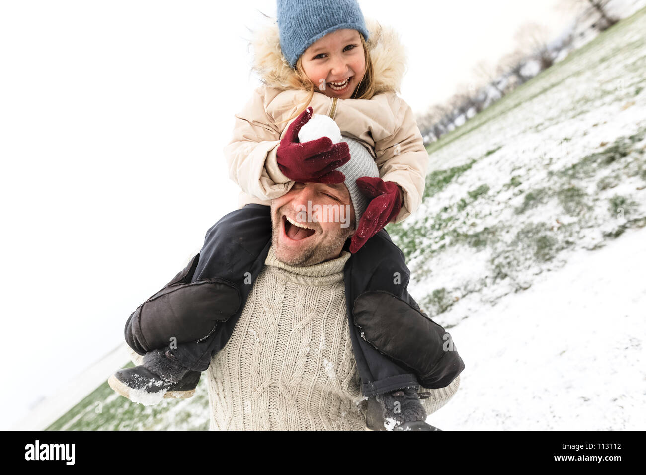 Playful father carrying daughter piggyback in winter landscape Stock ...