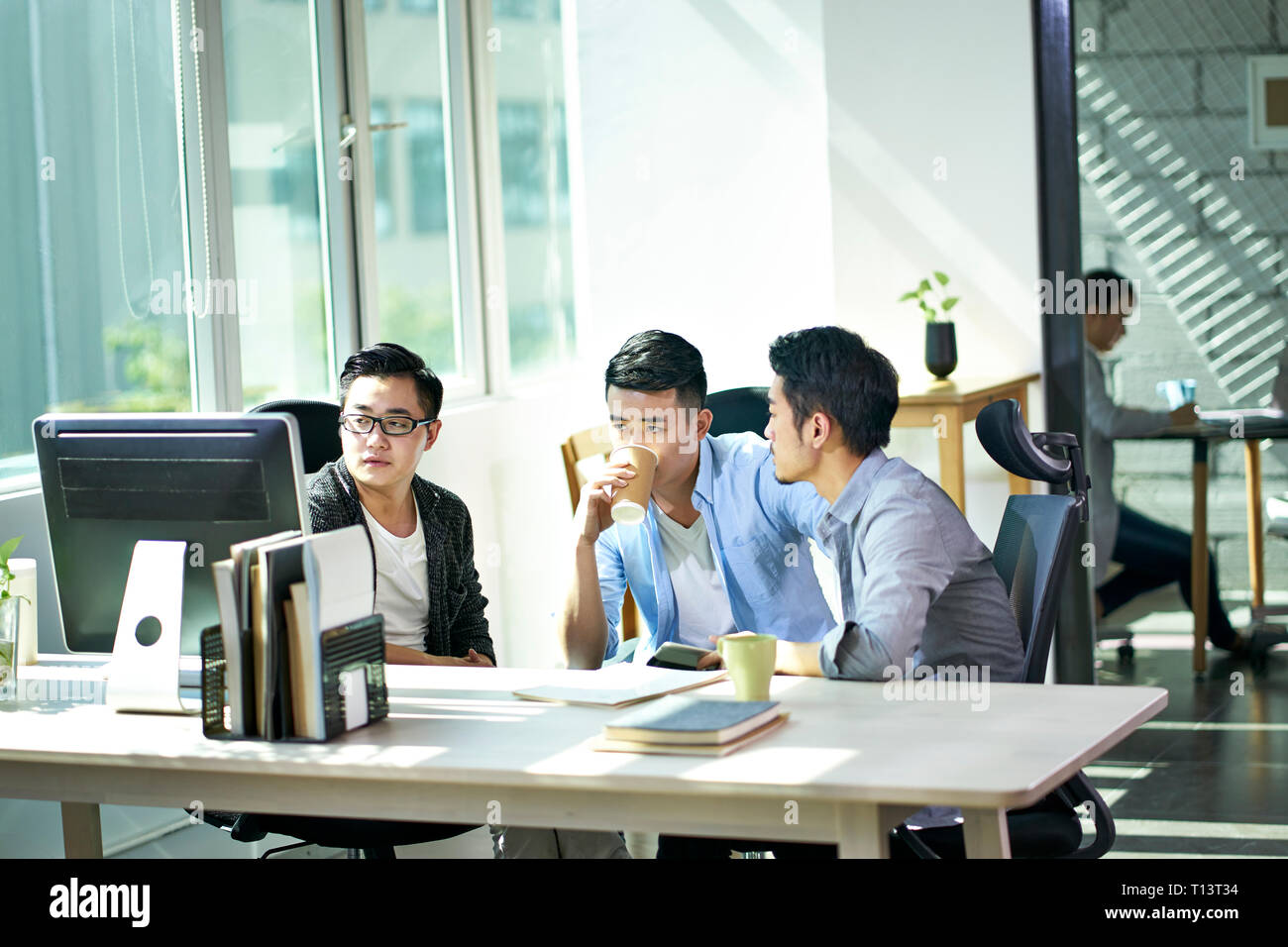 three young asian corporate executives working together discussing ...