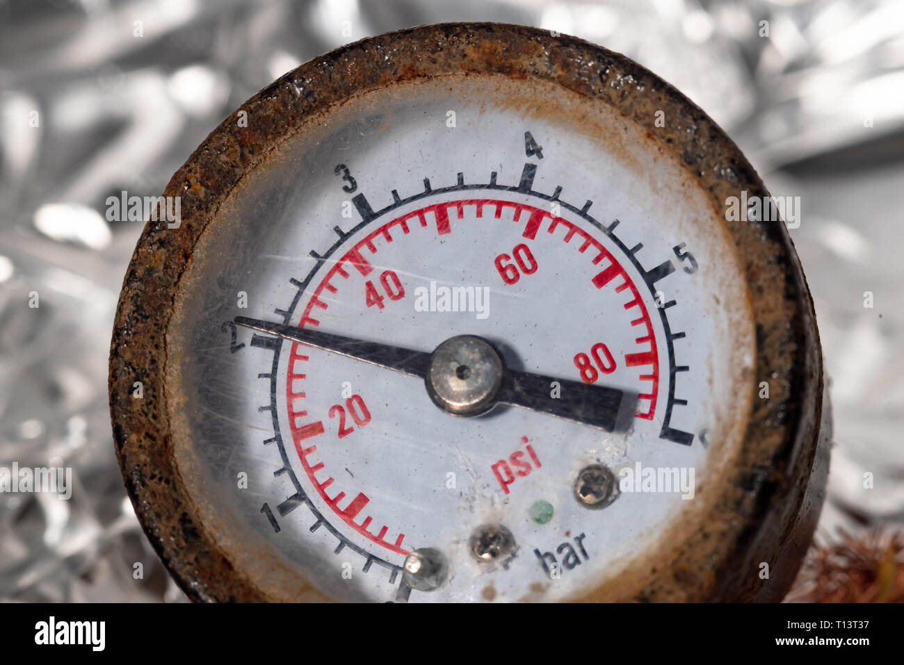 old rusty tire pressure gauge with red numbers on a white background ...