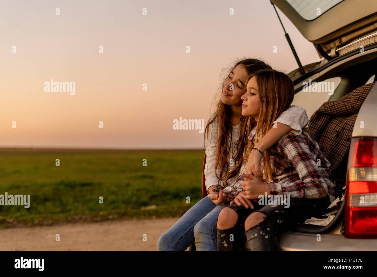 Two happy sisters sitting at opened tail watching sunset together Stock ...