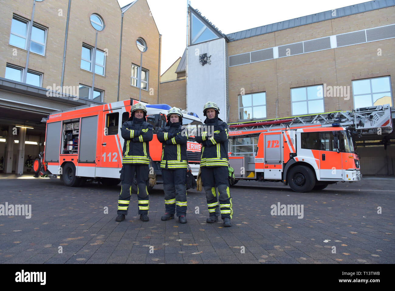 Portrait of three confident firefighters standing on yard in front of ...