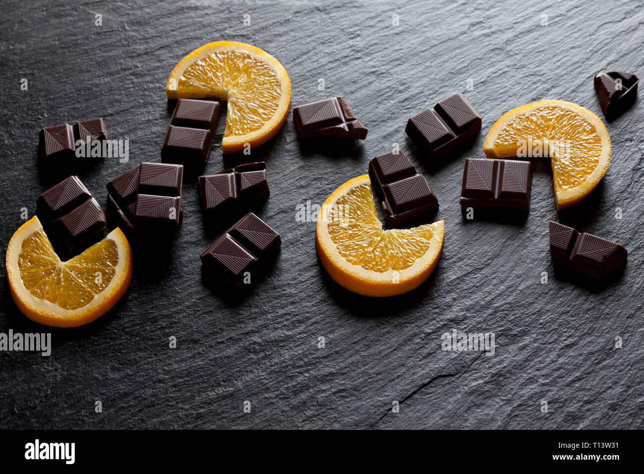 Cocolate pieces with orange slices on black slate Stock Photo - Alamy